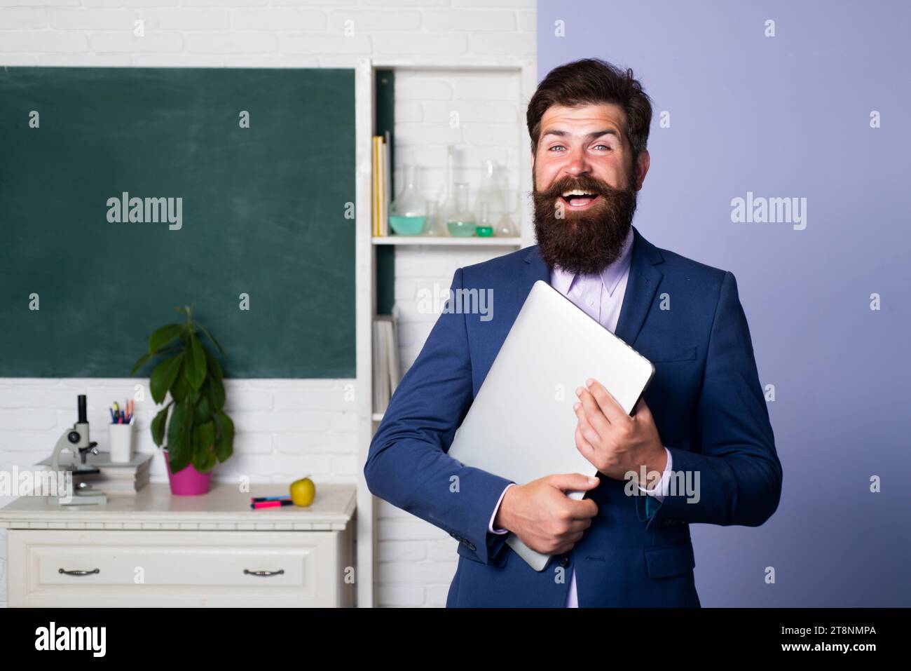 Portrait of funny teacher in classroom. Handsome bearded man near ...
