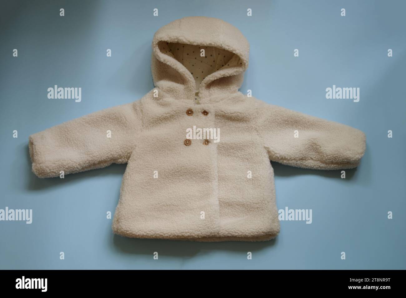White baby coat against blue background Stock Photo - Alamy
