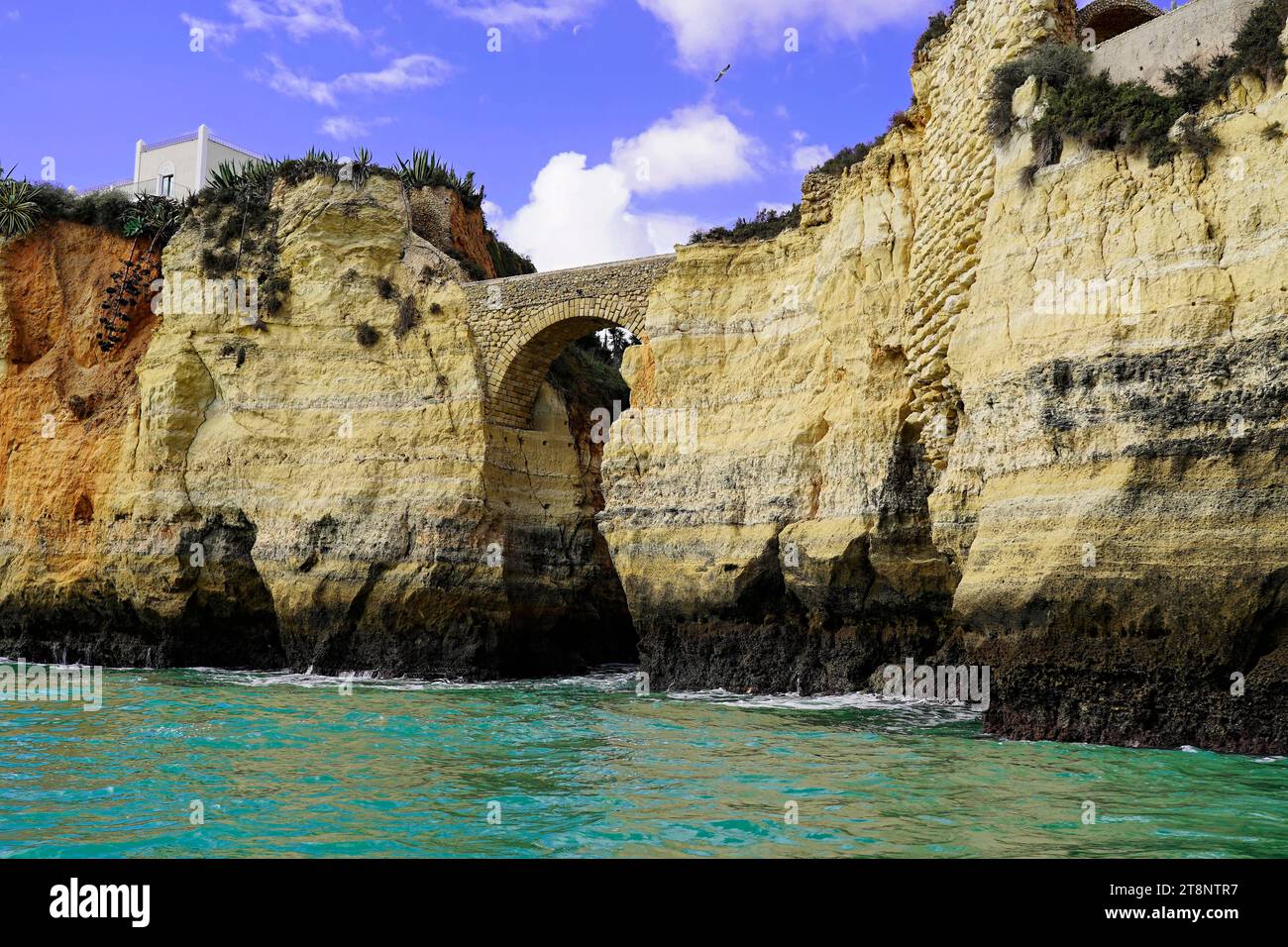 Historic Roman stone bridge at Praia da Batata beach in the rocky coast ...
