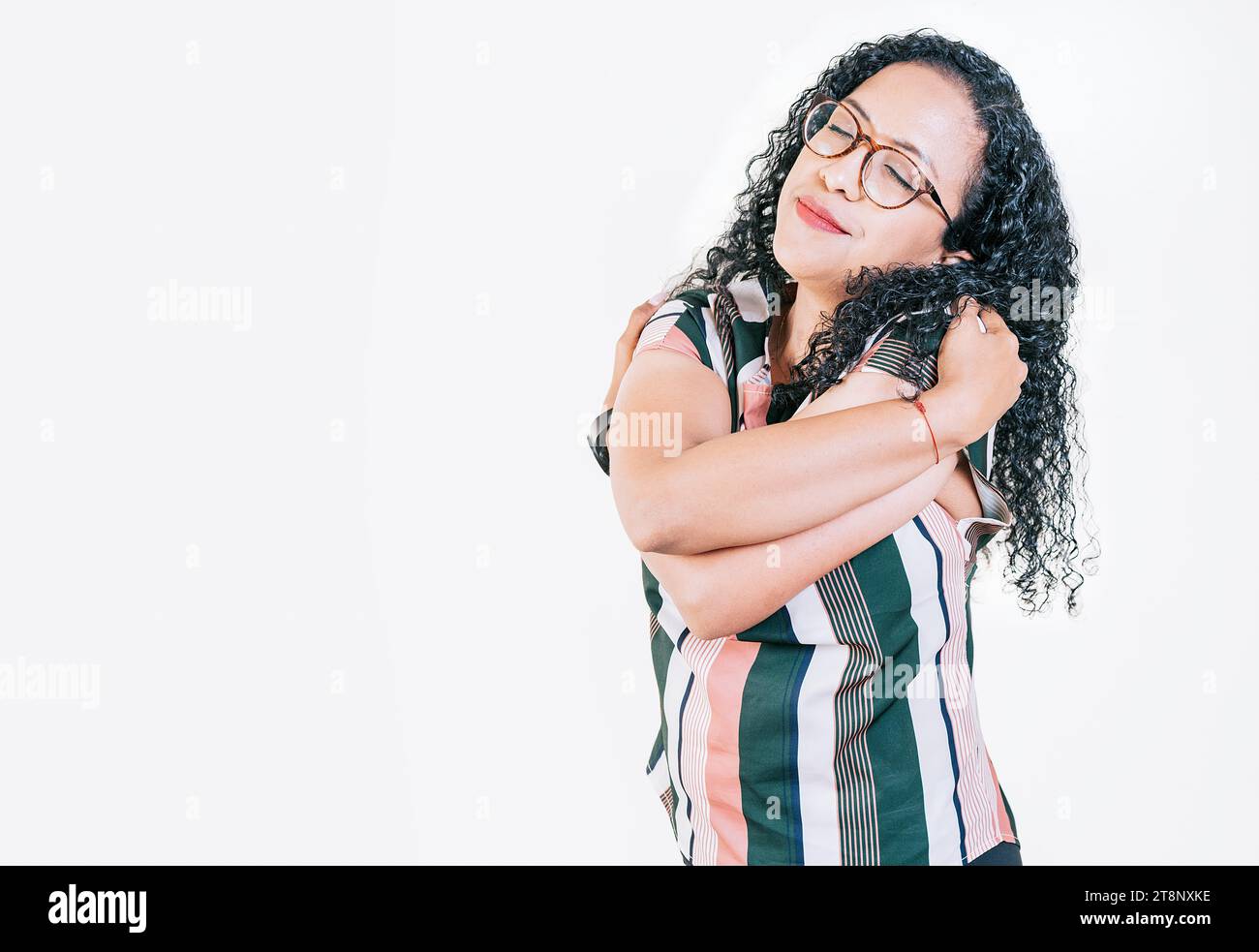 Afro woman hugging herself isolated. Smiling young woman hugging ...