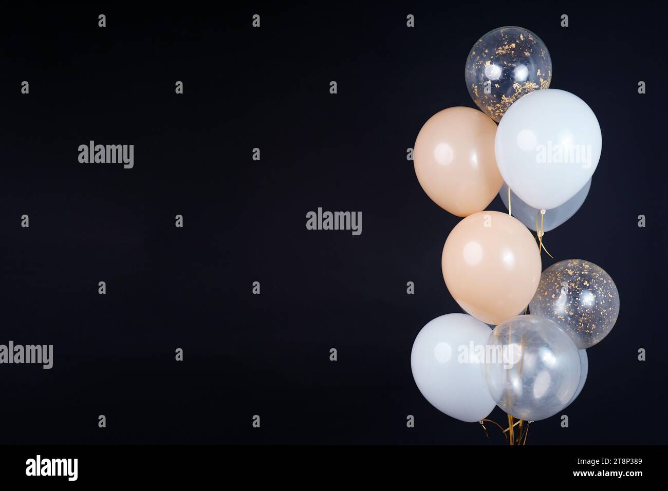 A bunch of balloons in white, beige and transparent colors on a dark ...