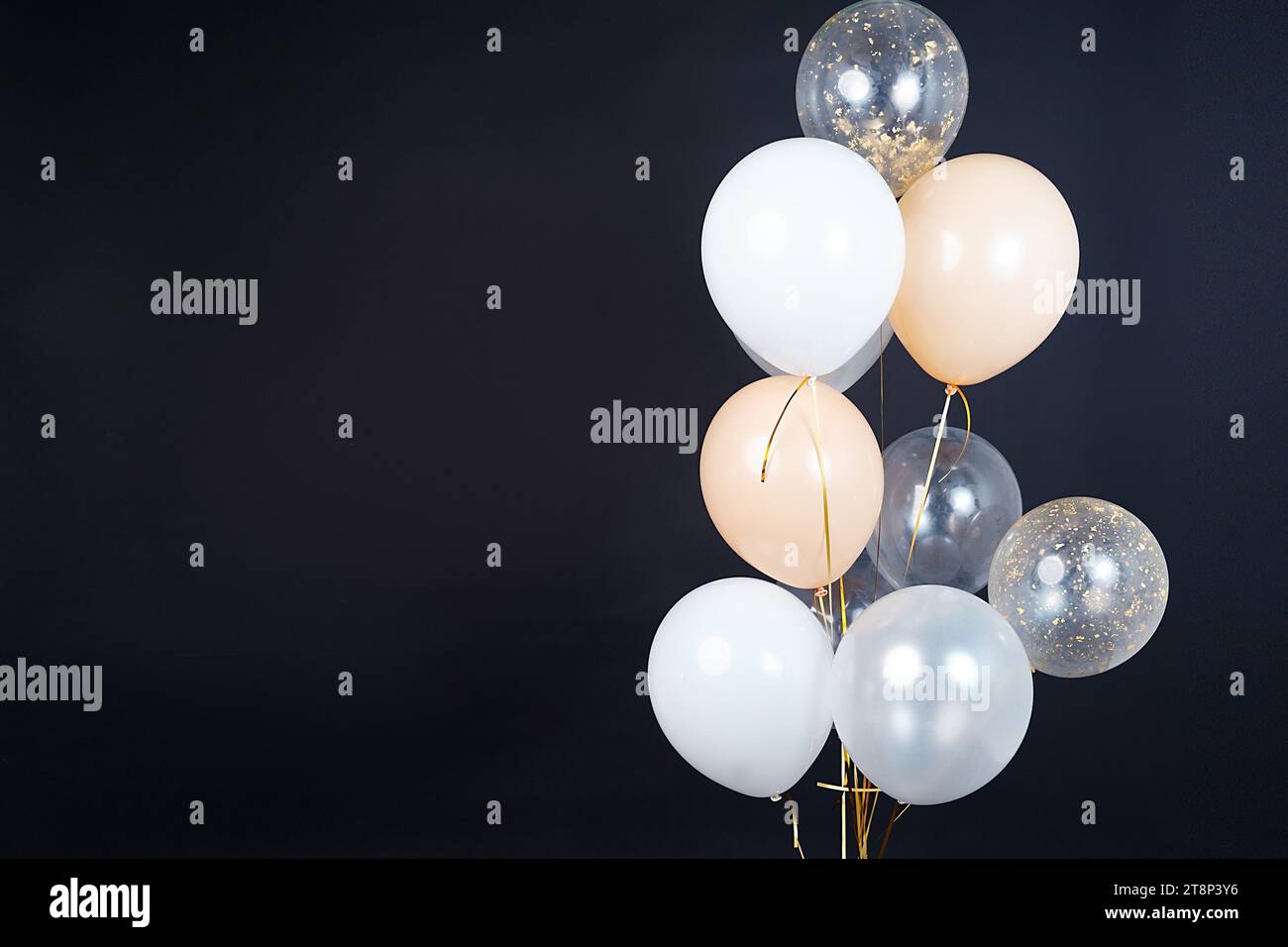 A bunch of balloons in white, beige and transparent colors on a dark ...