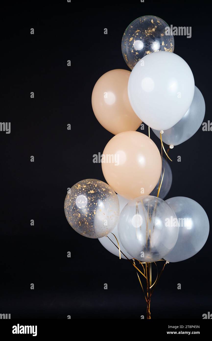 A bunch of balloons in white, beige and transparent colors on a dark ...