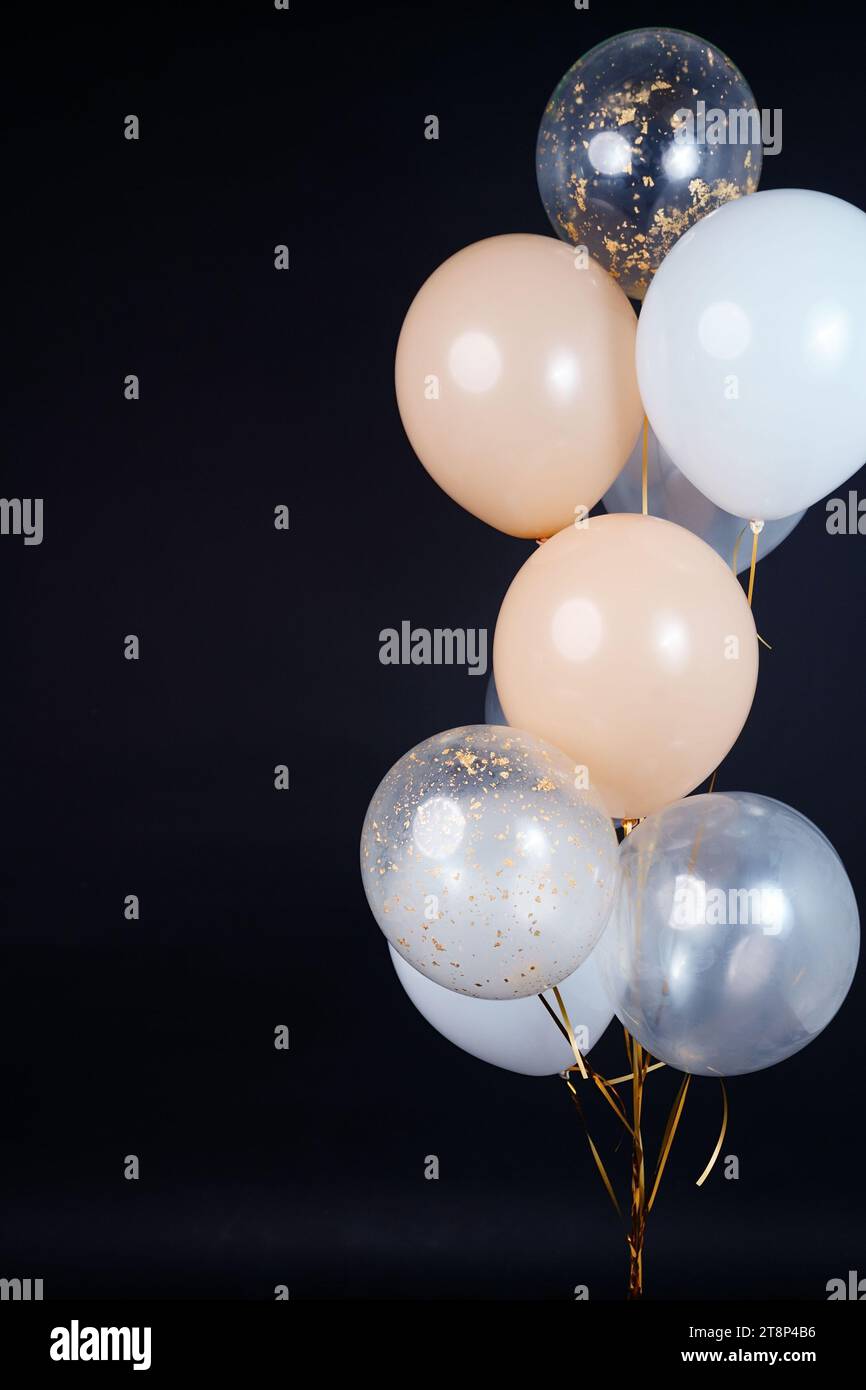 A bunch of balloons in white, beige and transparent colors on a dark ...