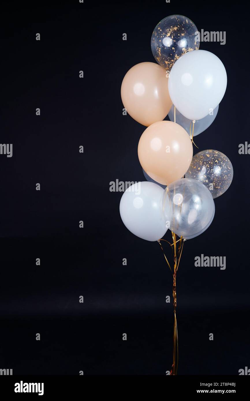 A bunch of balloons in white, beige and transparent colors on a dark ...