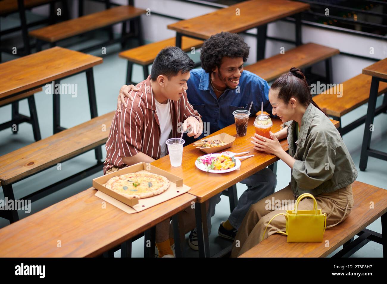 Diverse group of friends joking around and laughing when having pizza ...