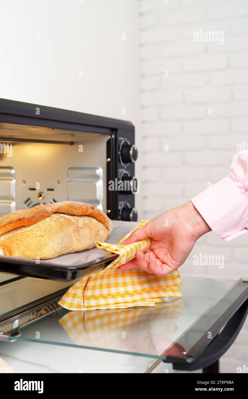 Woman's hands taking fresh bakery out of mini oven Stock Photo - Alamy