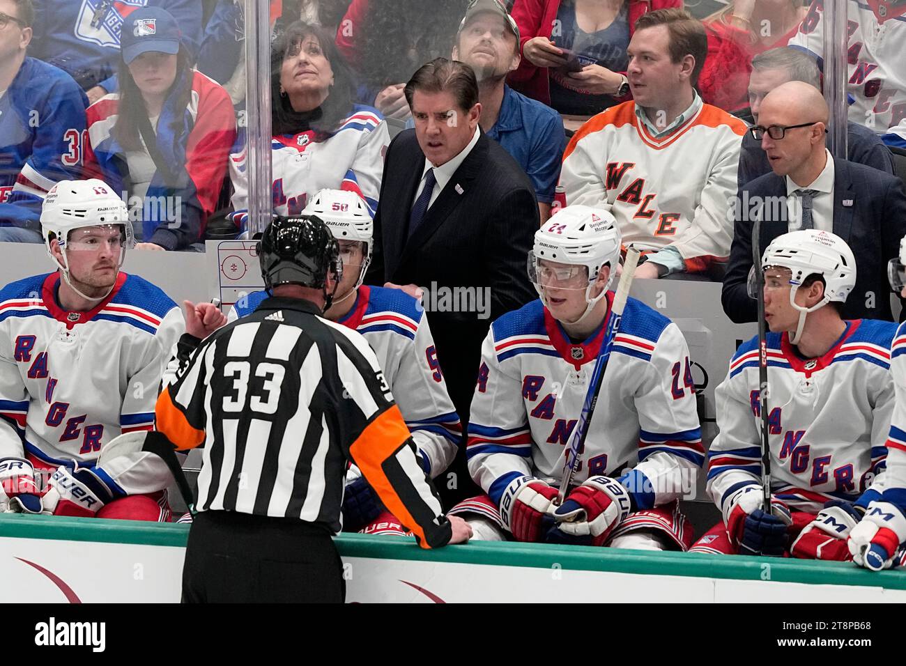 Referee Kevin Pollock (33) talks to New York Rangers head coach Peter Laviolette, center rear ...