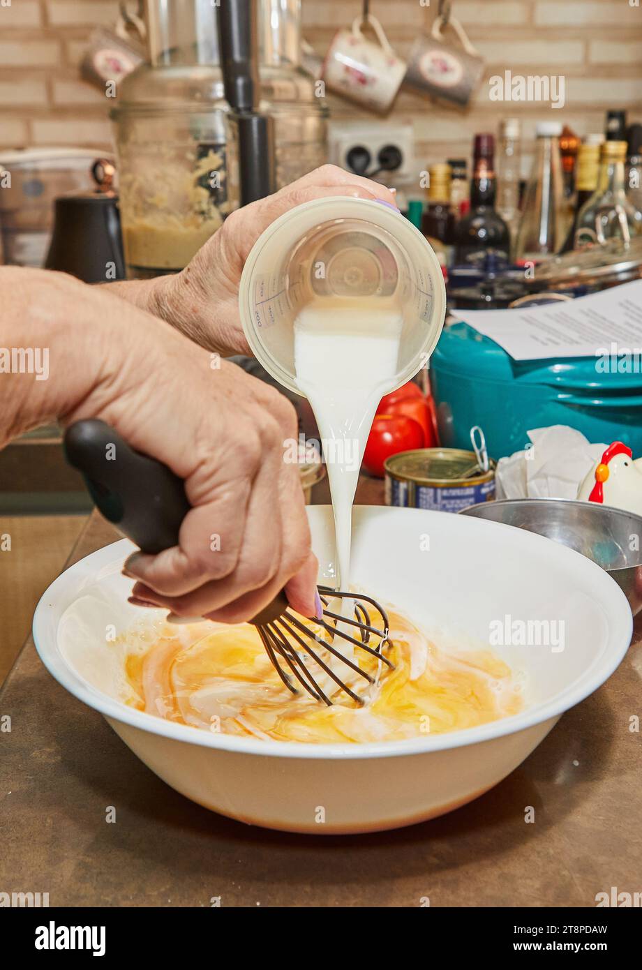 Chef pours milk from measuring cup into whisked eggs Stock Photo - Alamy
