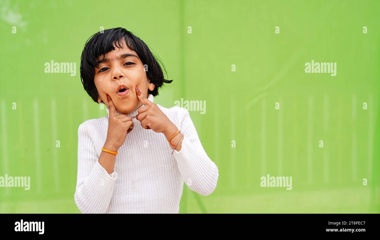 Photo of sweet blond little girl point smile isolated on green color ...