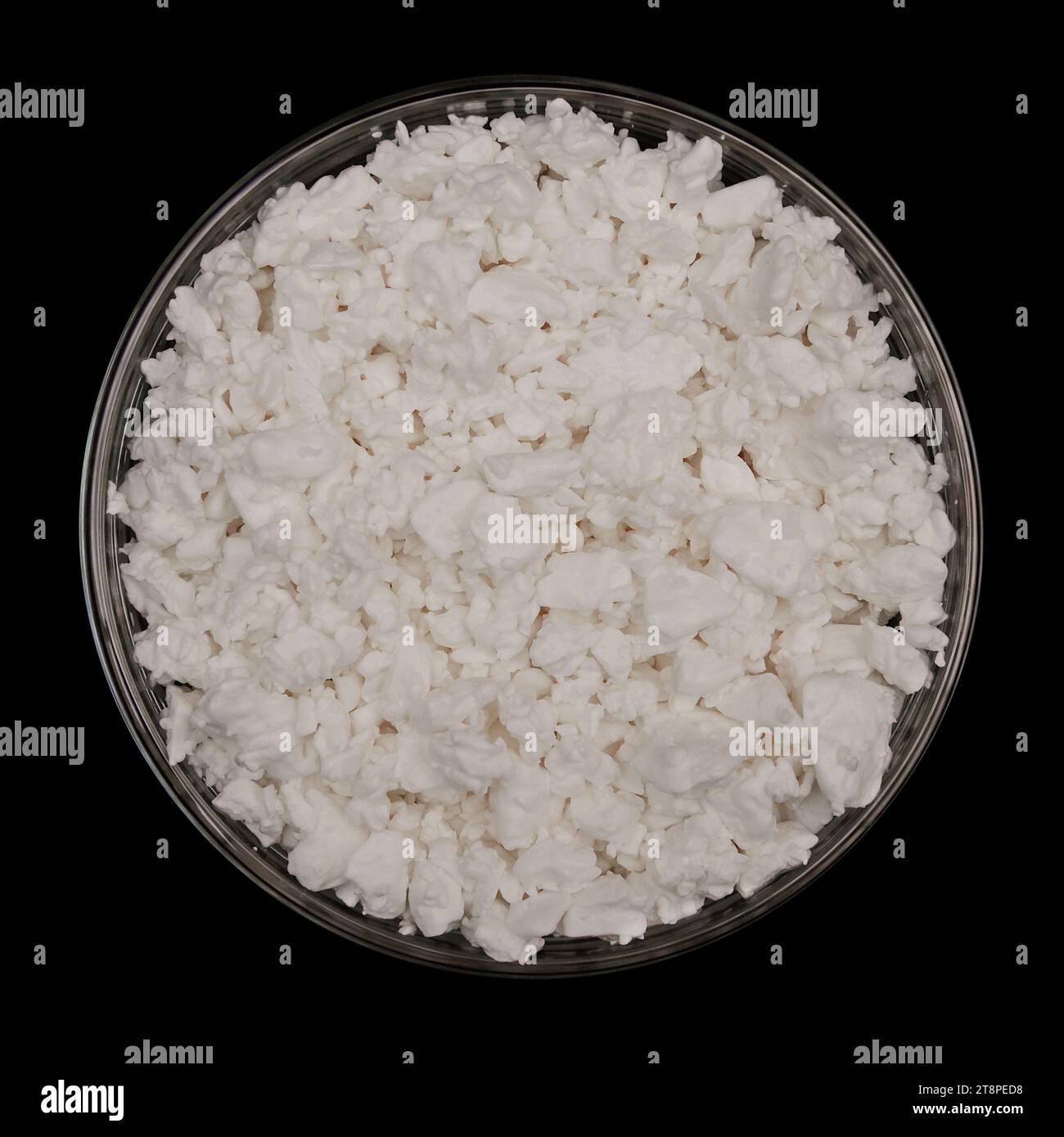 Cottage cheese in glass bowl isolated on black background. Top view of ...