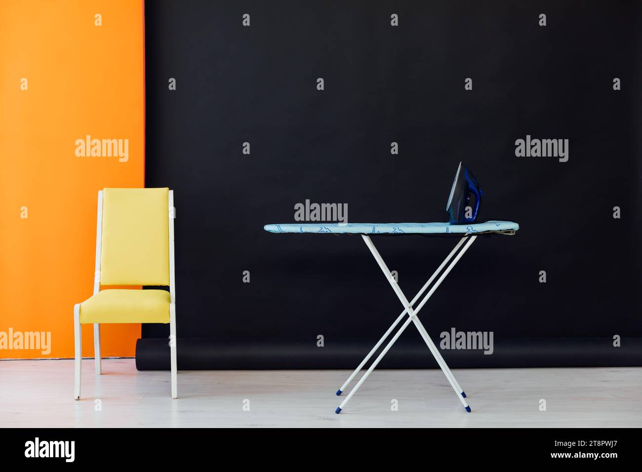 Ironing board with iron on black background yellow chair Stock Photo ...