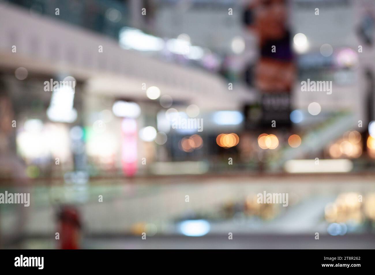 Blurry view of a bustling mall interior with various shops and ...