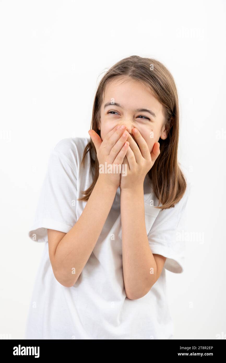 A girl laughs cheerfully, covering her face with her hand on a white ...