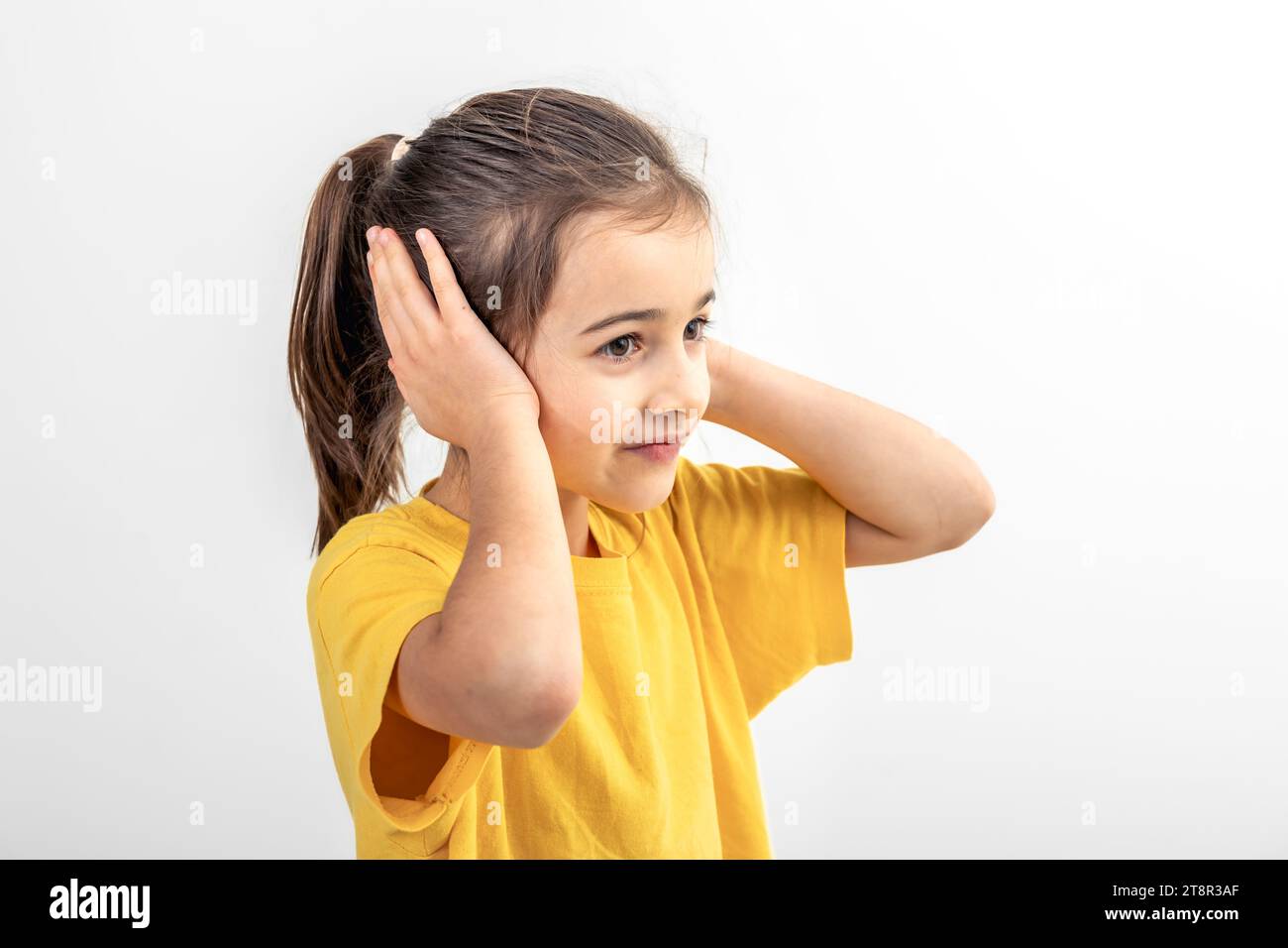 Little Caucasian girl covered her ears on a white background isolated ...