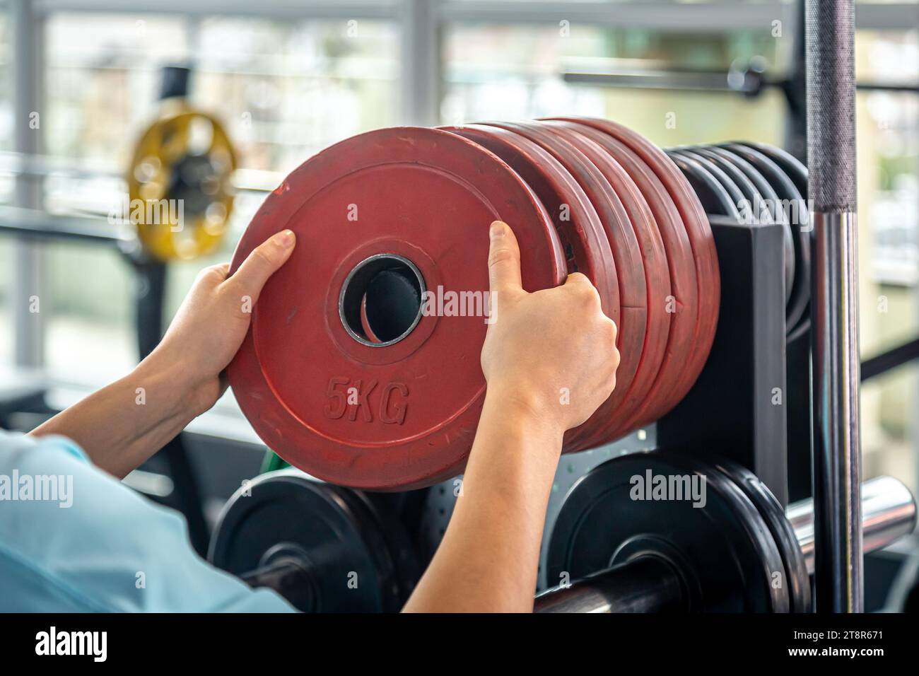 A muscular sportswoman putting weight plates in a gym for bodybuilding ...