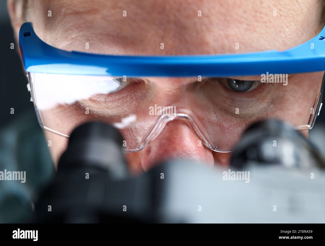 Male laboratory worker eyes looking at microscope wearing goggles Stock ...