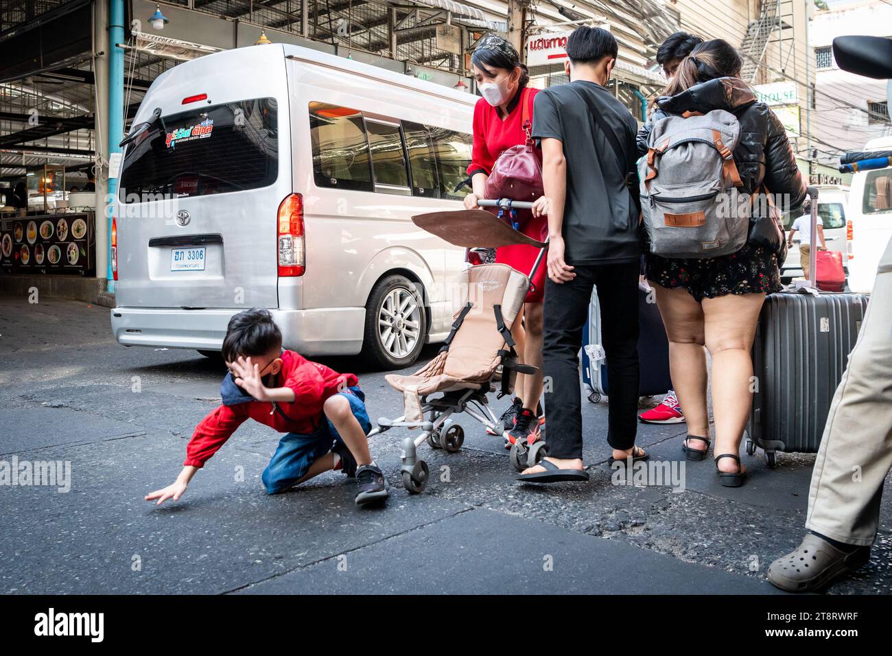 A young boy takes a tumble falling from his pram in the busy streets of ...