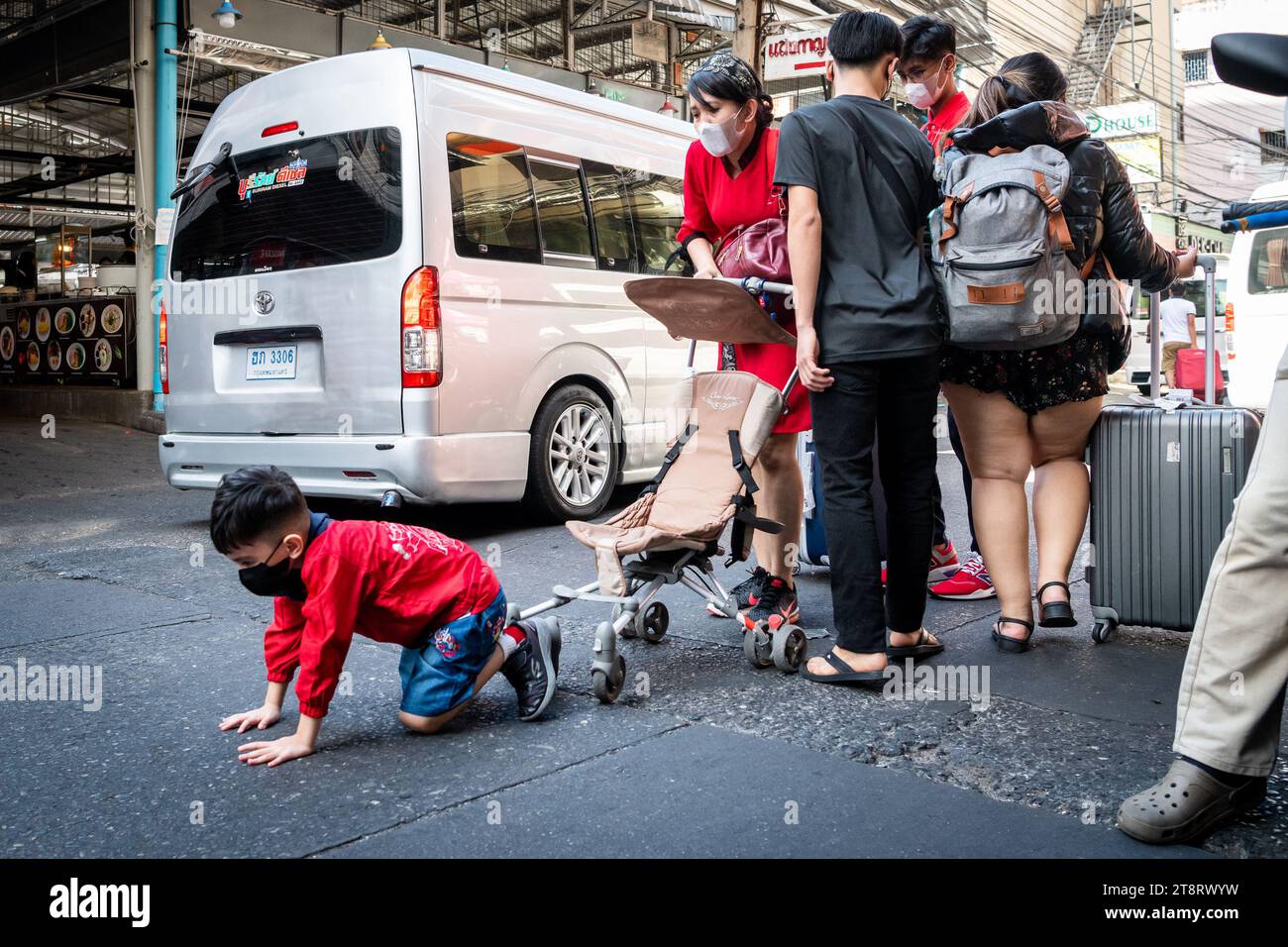 A young boy takes a tumble falling from his pram in the busy streets of ...