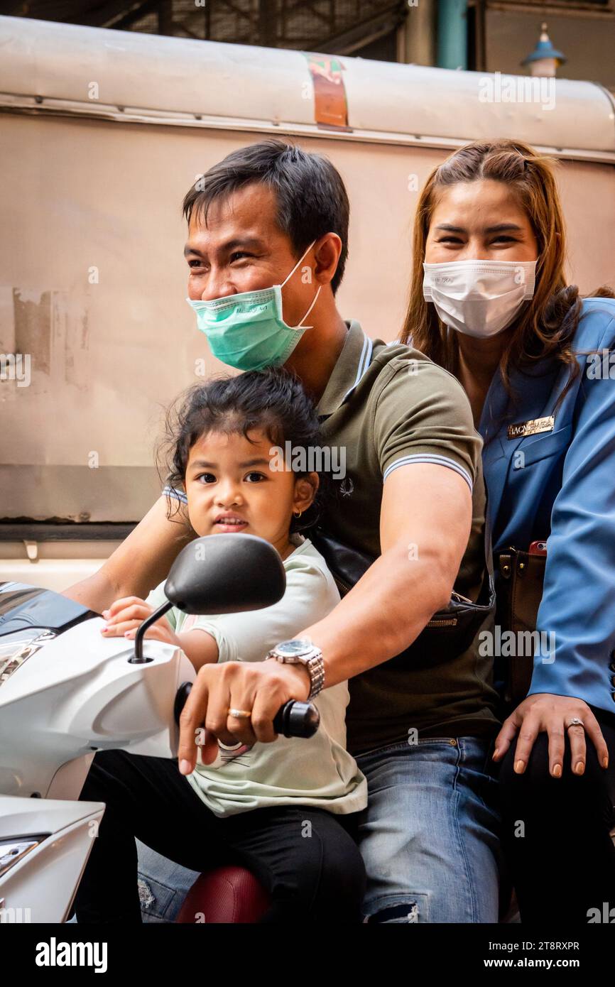A young Thai family make their way through Pratunam Market Bangkok ...