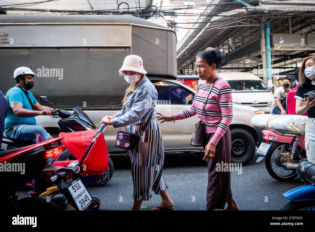 Pedestrians, shoppers and market workers busily go about their business ...