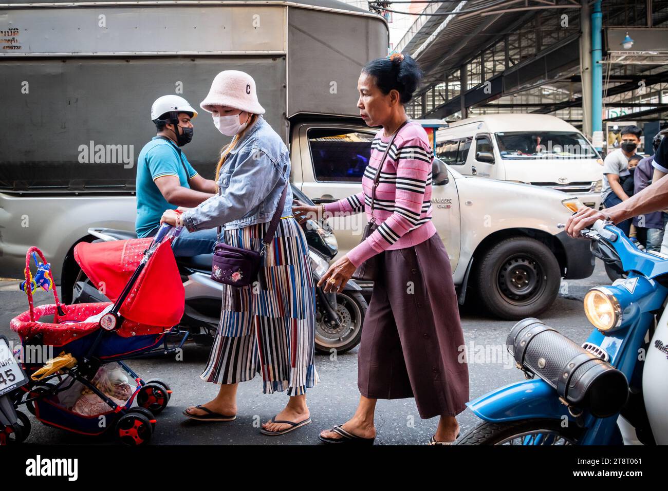 Pedestrians, shoppers and market workers busily go about their business ...