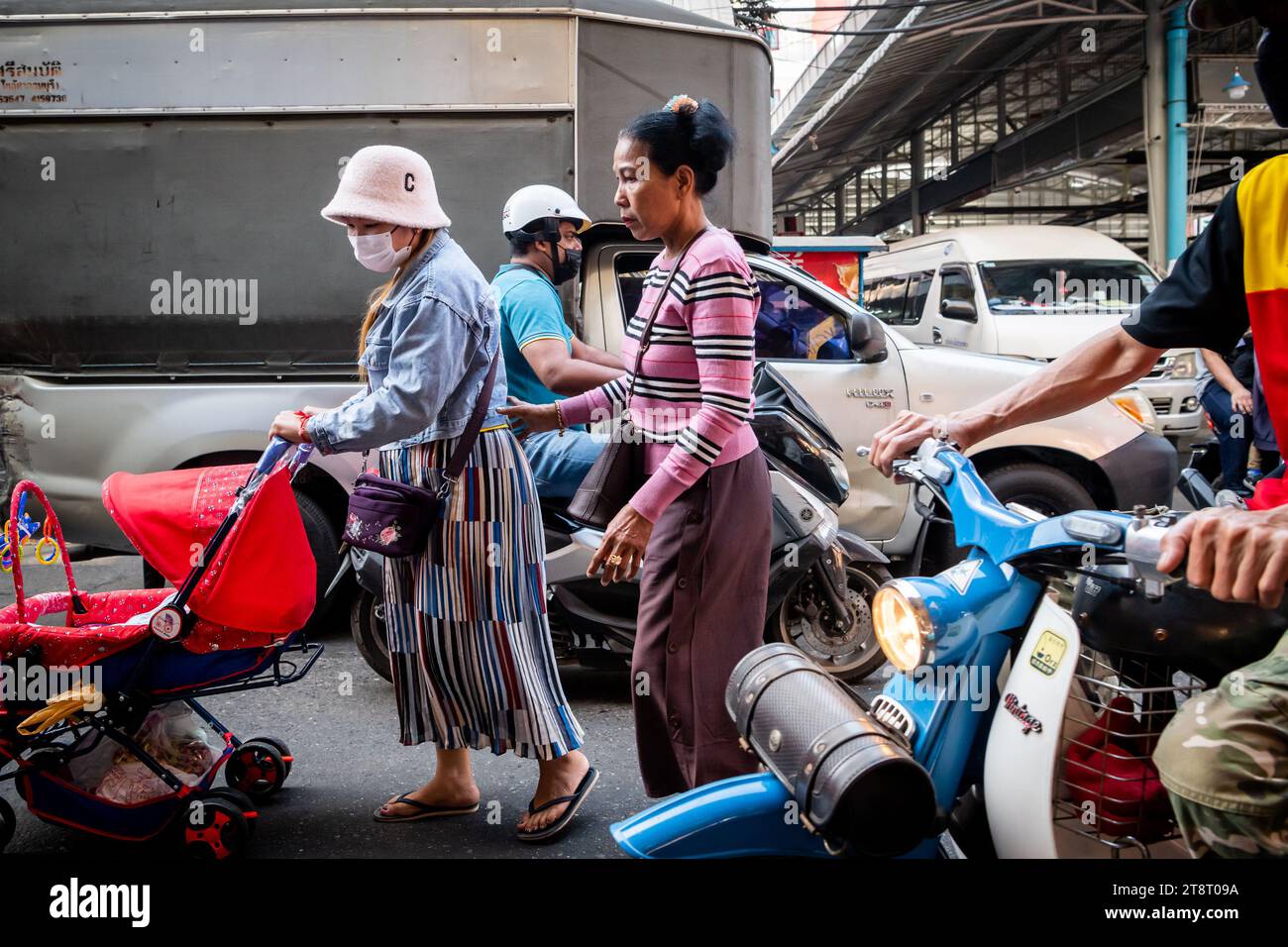 Pedestrians, shoppers and market workers busily go about their business ...