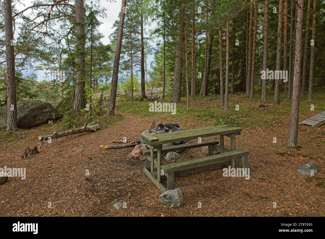 Camping fire behind table and benches on the island of Linlo in forest ...