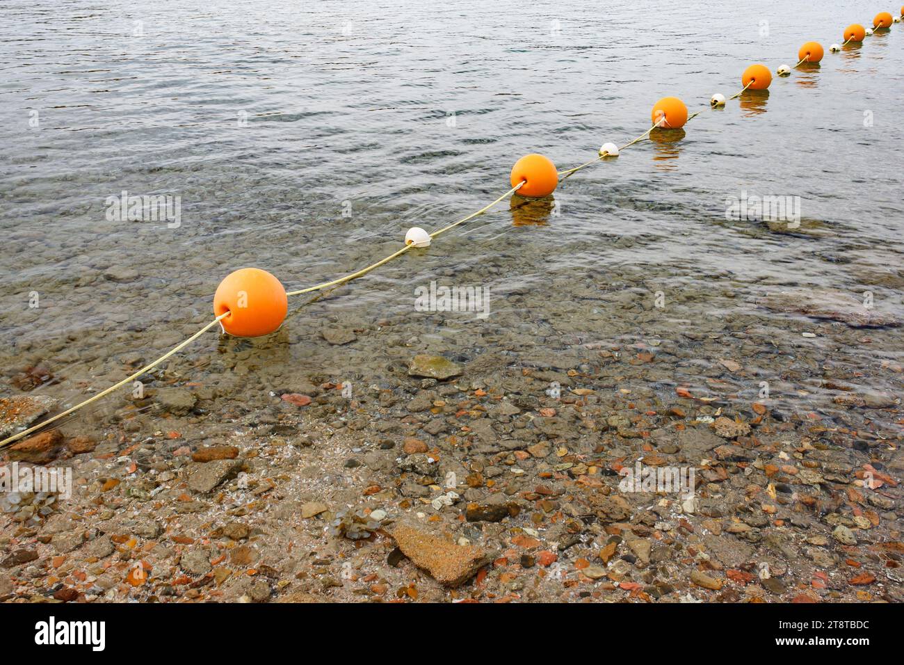 Orange spherical buoys on a rope in the sea, fencing a safe swimming ...