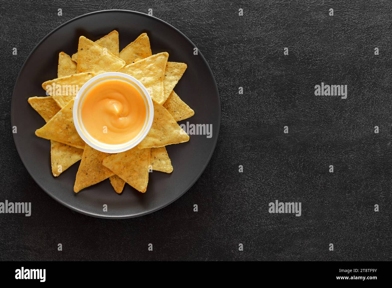 Nachos on grey plate and cheese salsa, on dark background, top view ...