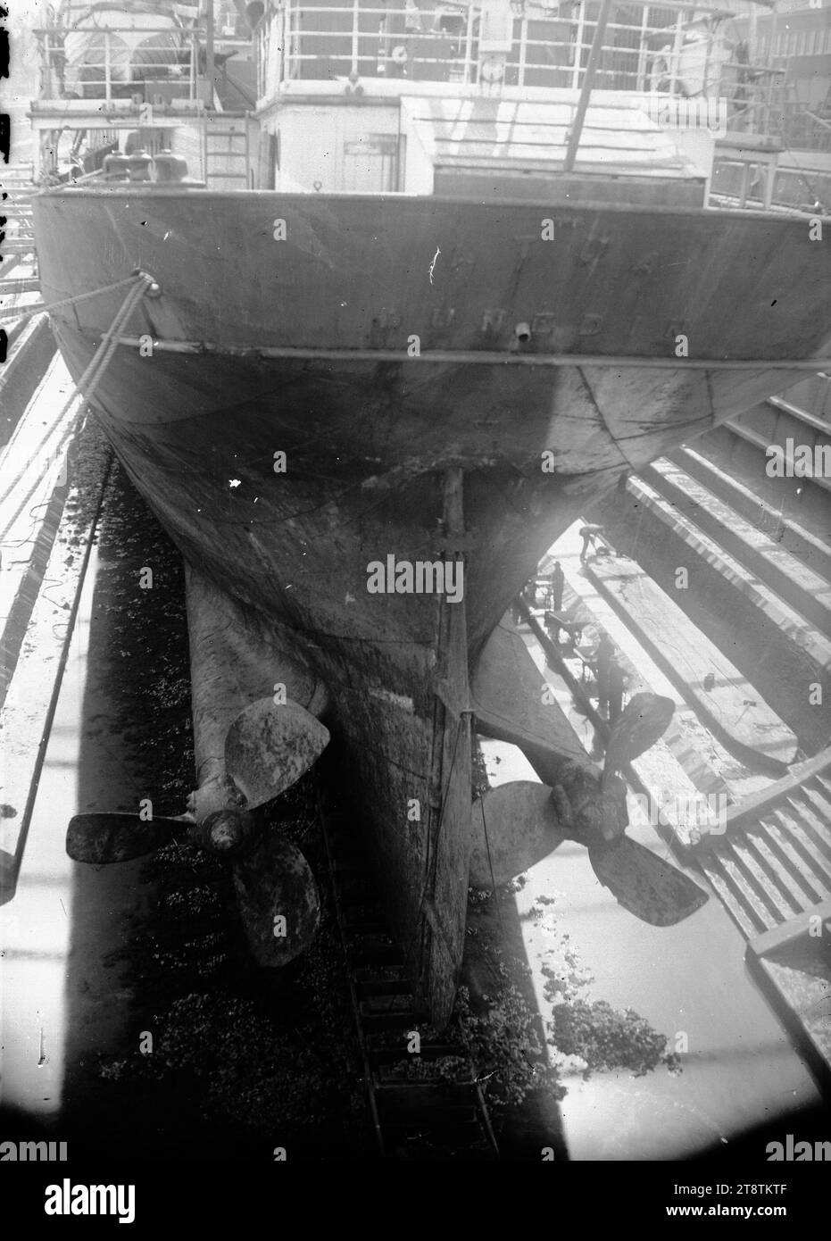 View of the stern of a ship showing the propellers with men working at ...