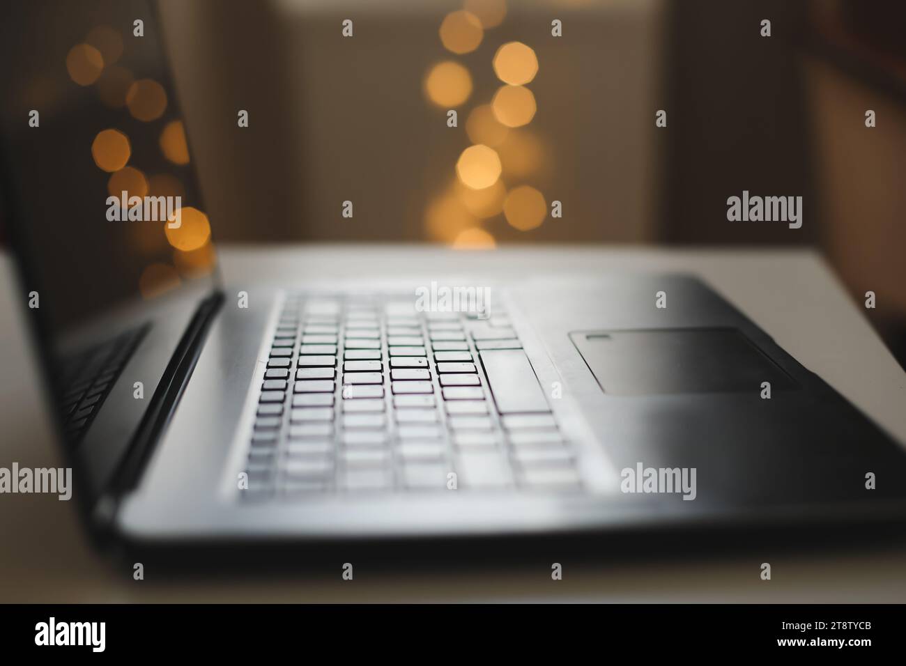 Close up of laptop keyboard with blank screen on a table by blurry ...