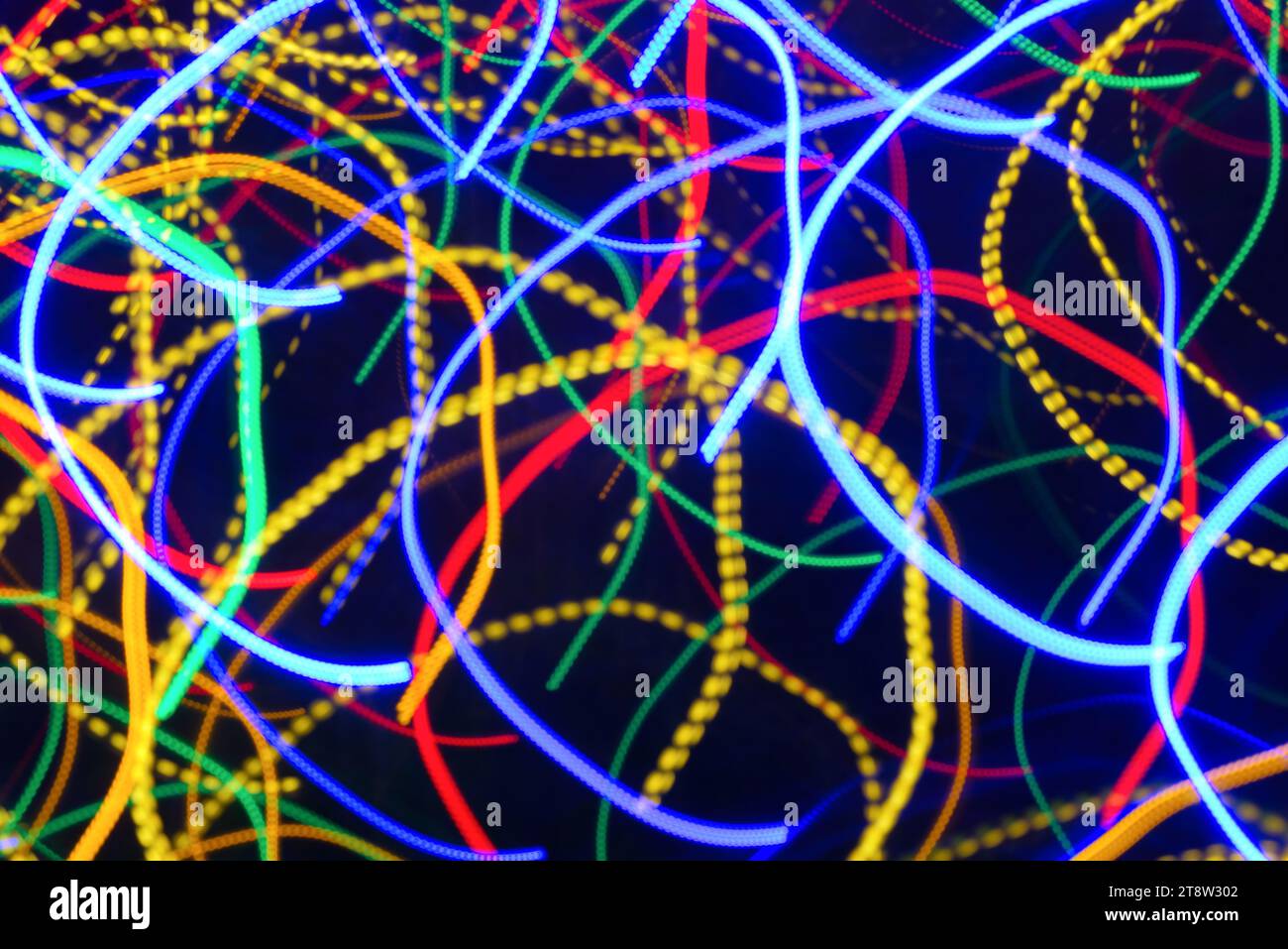 Blurred multi coloured light patterns streaks against a dark background ...