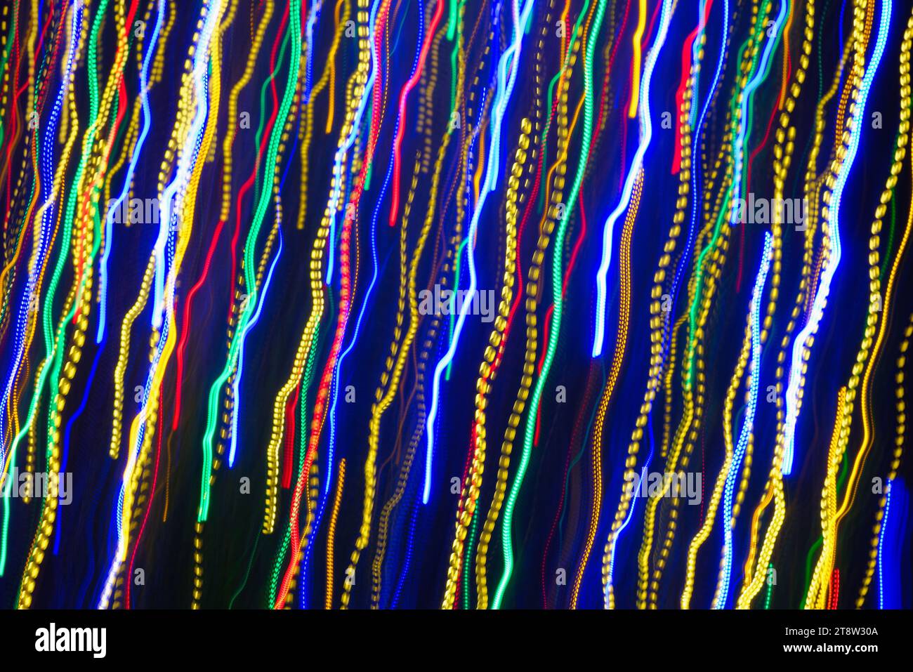 Blurred multi coloured light patterns streaks against a dark background ...
