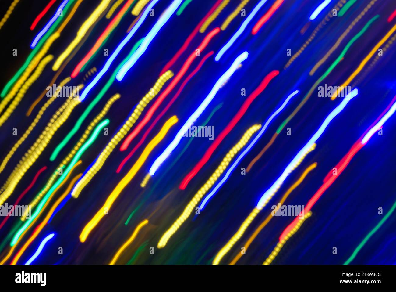 Blurred multi coloured light patterns streaks against a dark background ...