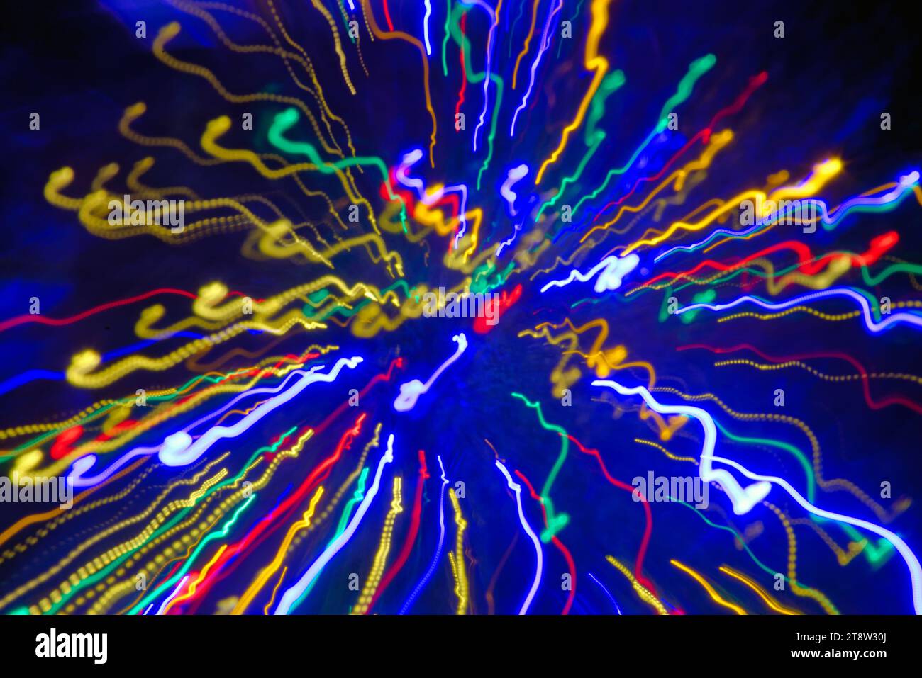 Blurred multi coloured light patterns streaks against a dark background ...