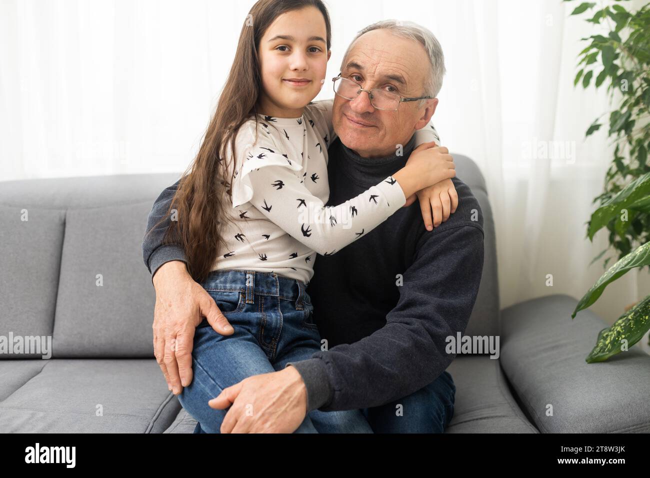 Family time. Pretty granddaughter hugging with her grandfather Stock ...
