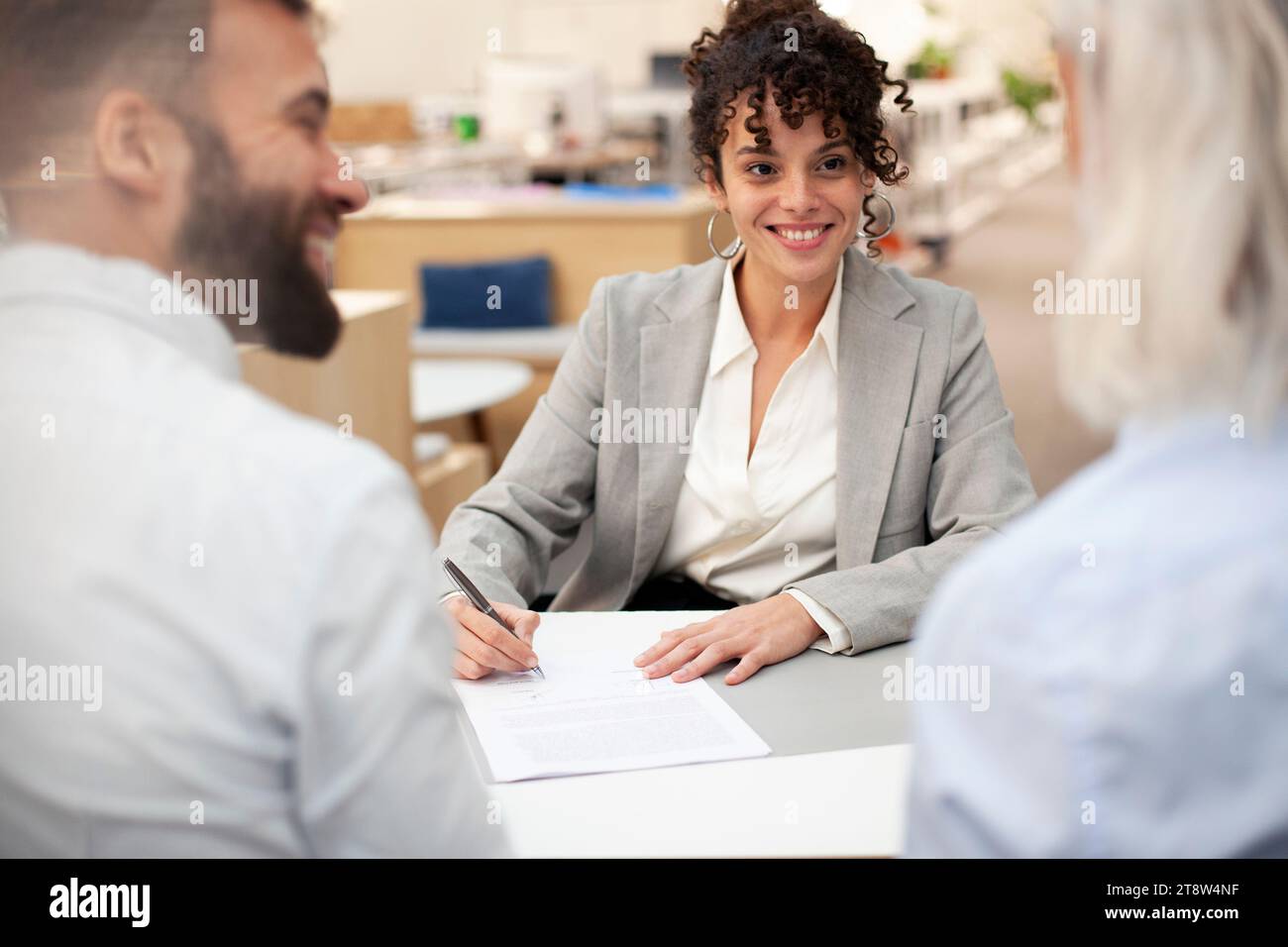 Bank worker signing contract while talking with clients Stock Photo - Alamy