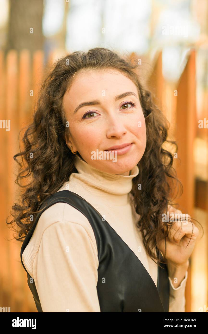 Autumn portrait of a beautiful happy curly woman in fall season ...