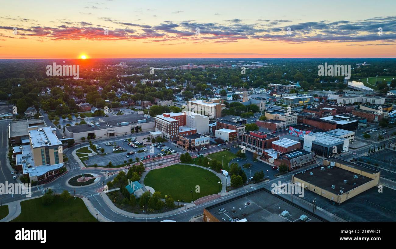 Muncie, IN sunset with golden sun over horizon aerial of downtown ...