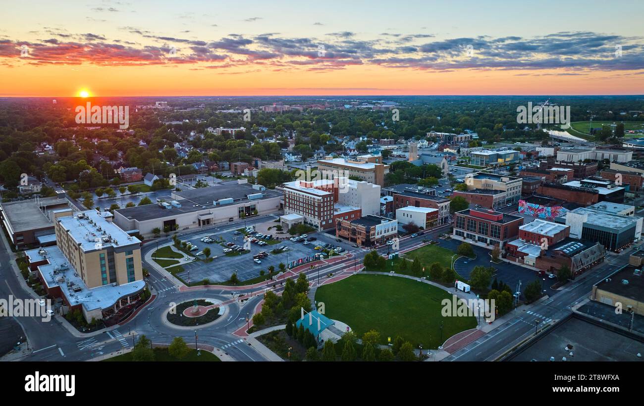 Muncie, IN sunset with golden sun over horizon aerial of downtown ...