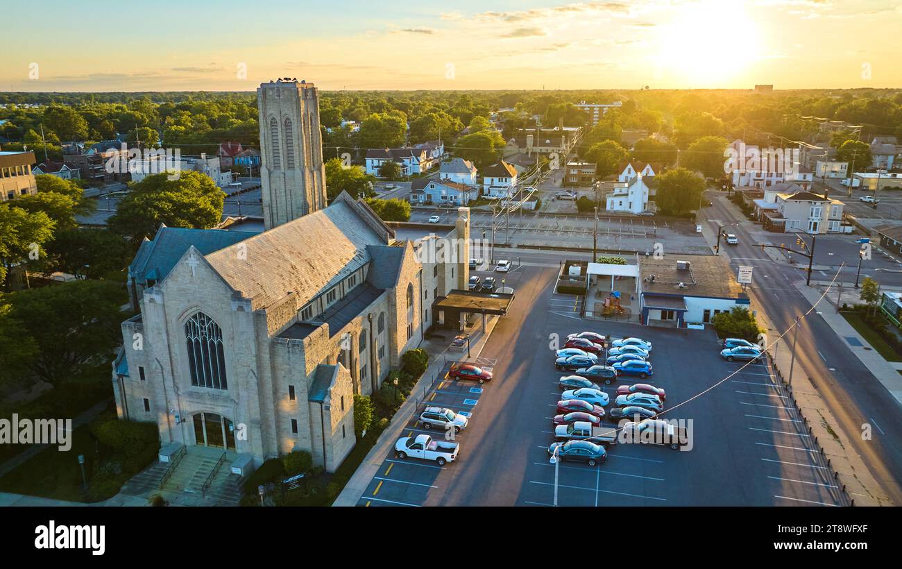 Glorious golden sun behind church at sunset aerial, Muncie IN with ...