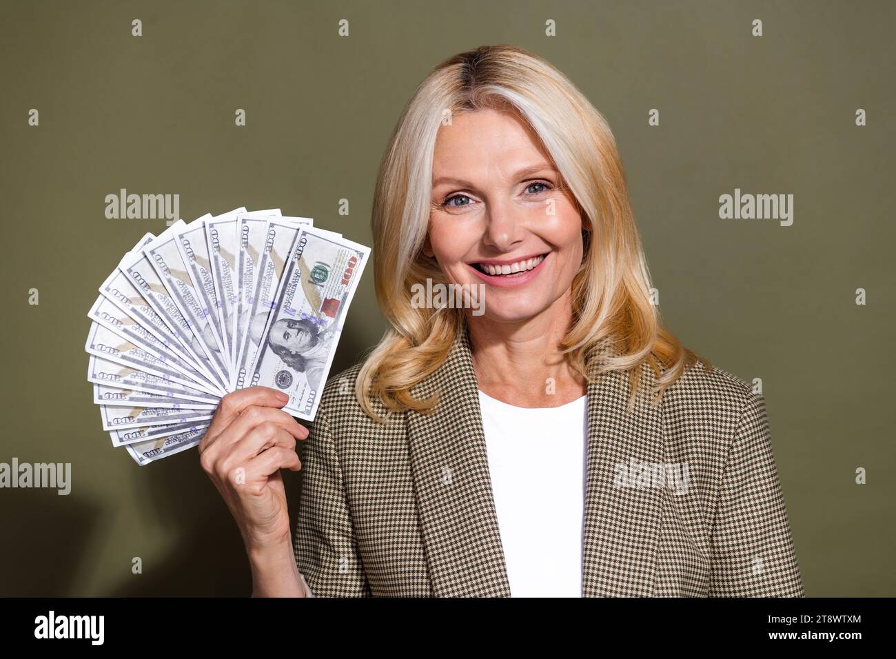 Portrait of cheerful businesswoman in jacket holding banknotes dollars ...