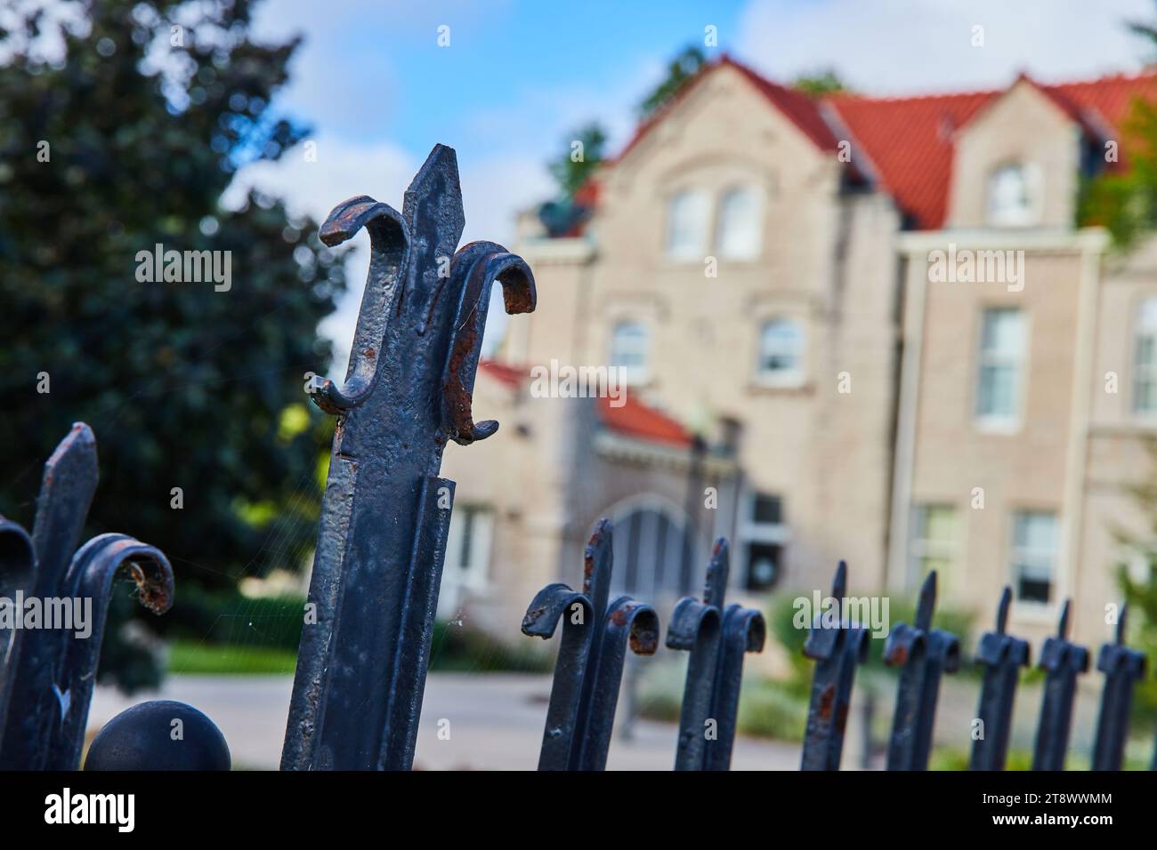 Black spike at top of fence close up with mansion in background at ...
