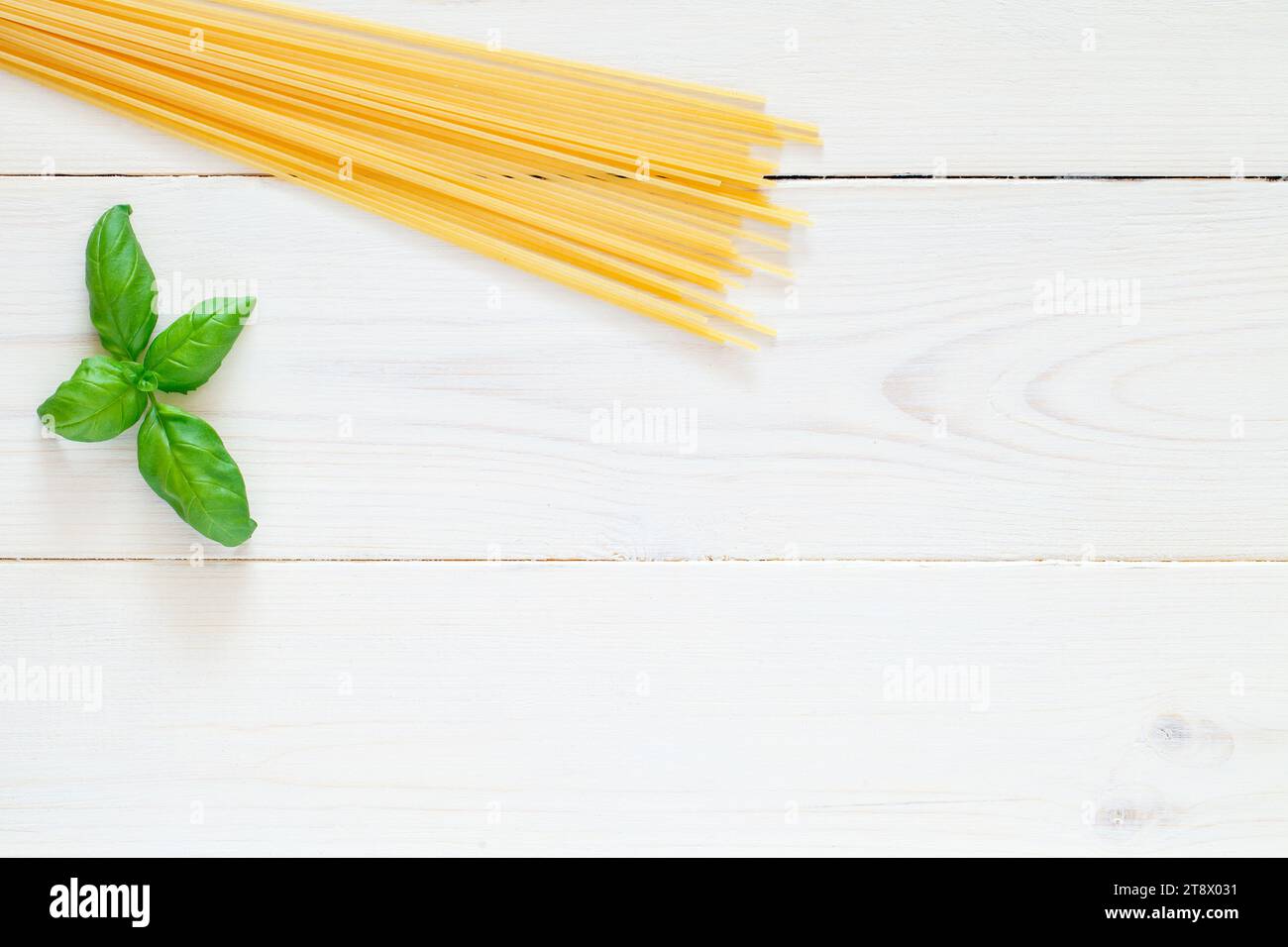 Spaghetti, raw pasta, basil leaf on white wooden board background, top ...