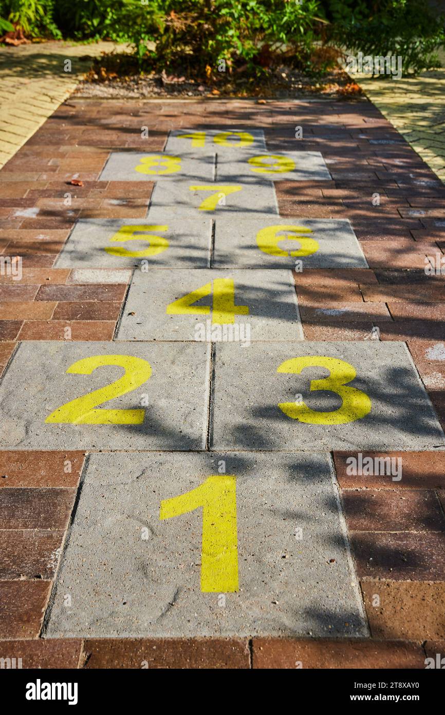 Hopscotch kids game on brick path with yellow numbers and shadow of ...