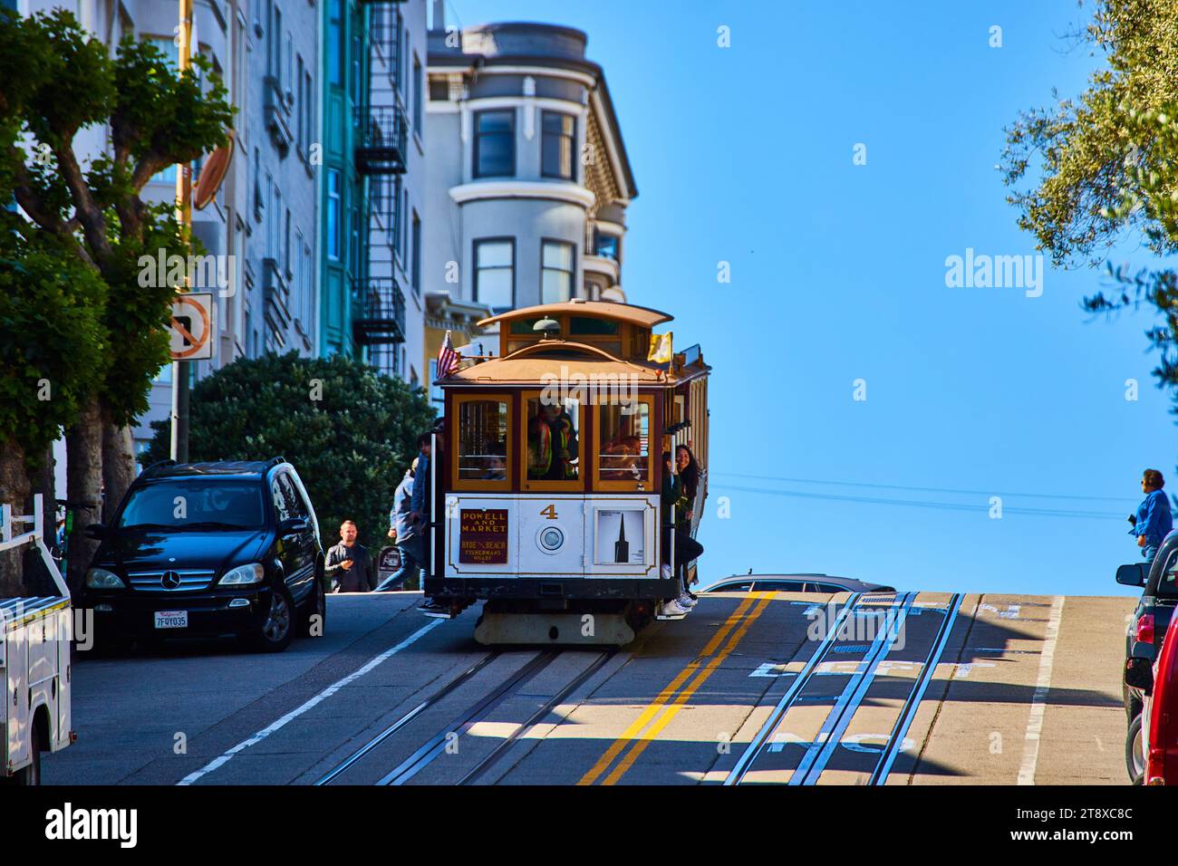 Red and tan trolley streetcar at top of hill heading down with ...