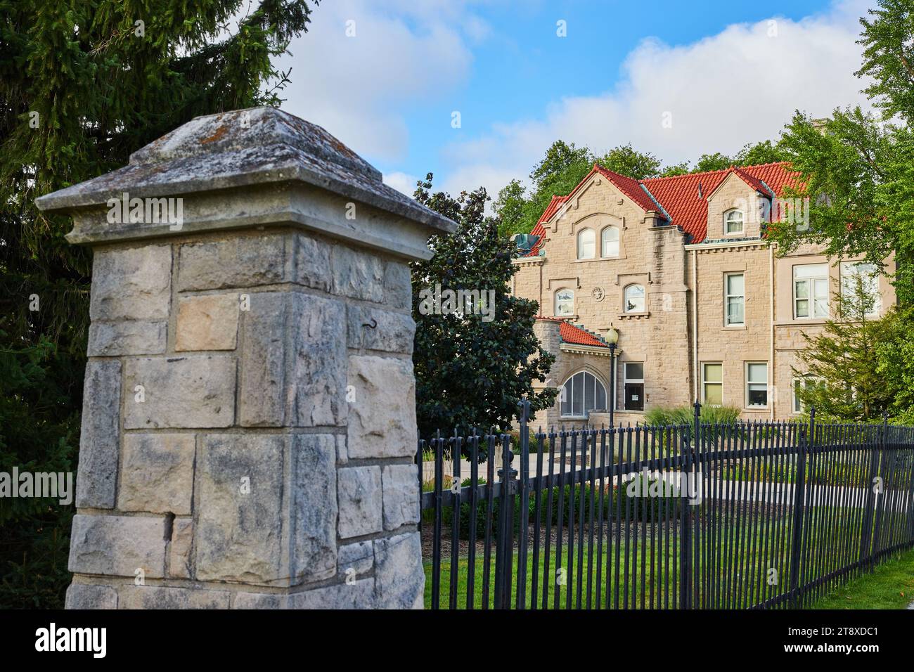 Brick or concrete column with black fence and mansion building at ...