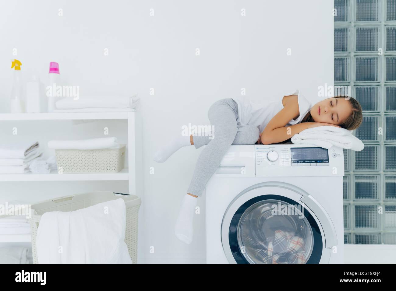 Girl naps on a washing machine in a serene white laundry room Stock ...