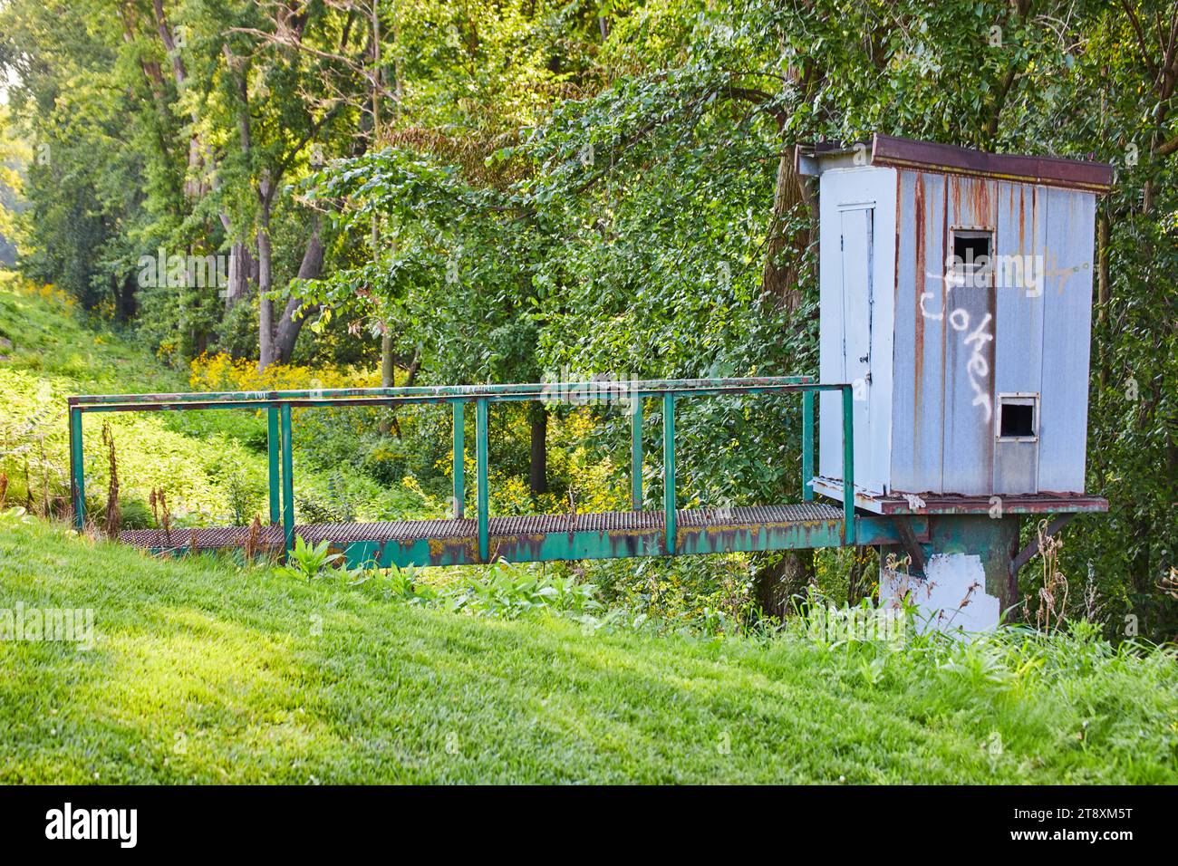 Spray painted Joker on side of rusty blue outhouse with green metal ...